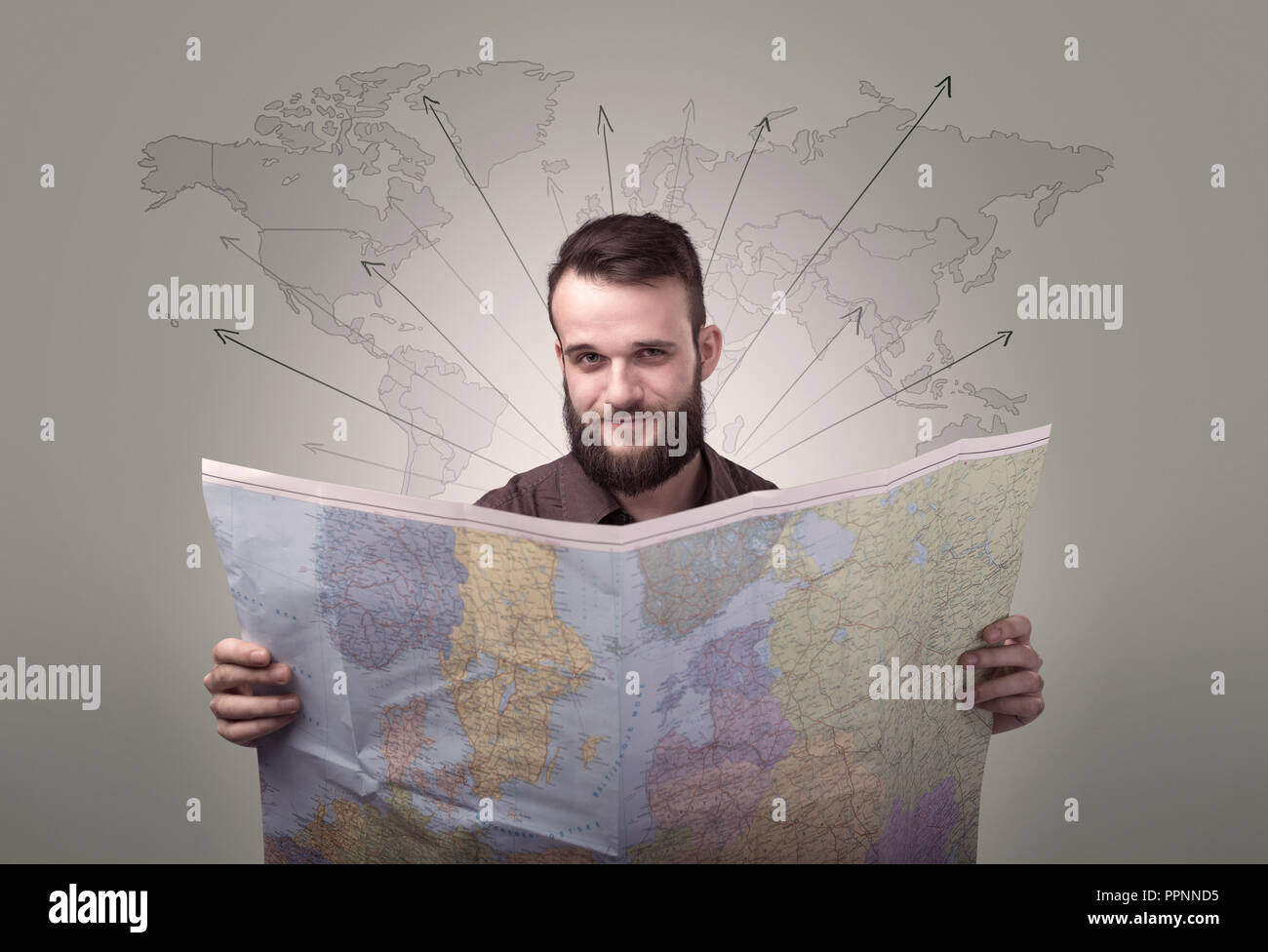Handsome young man holding a map with world map and arrows behind him ...