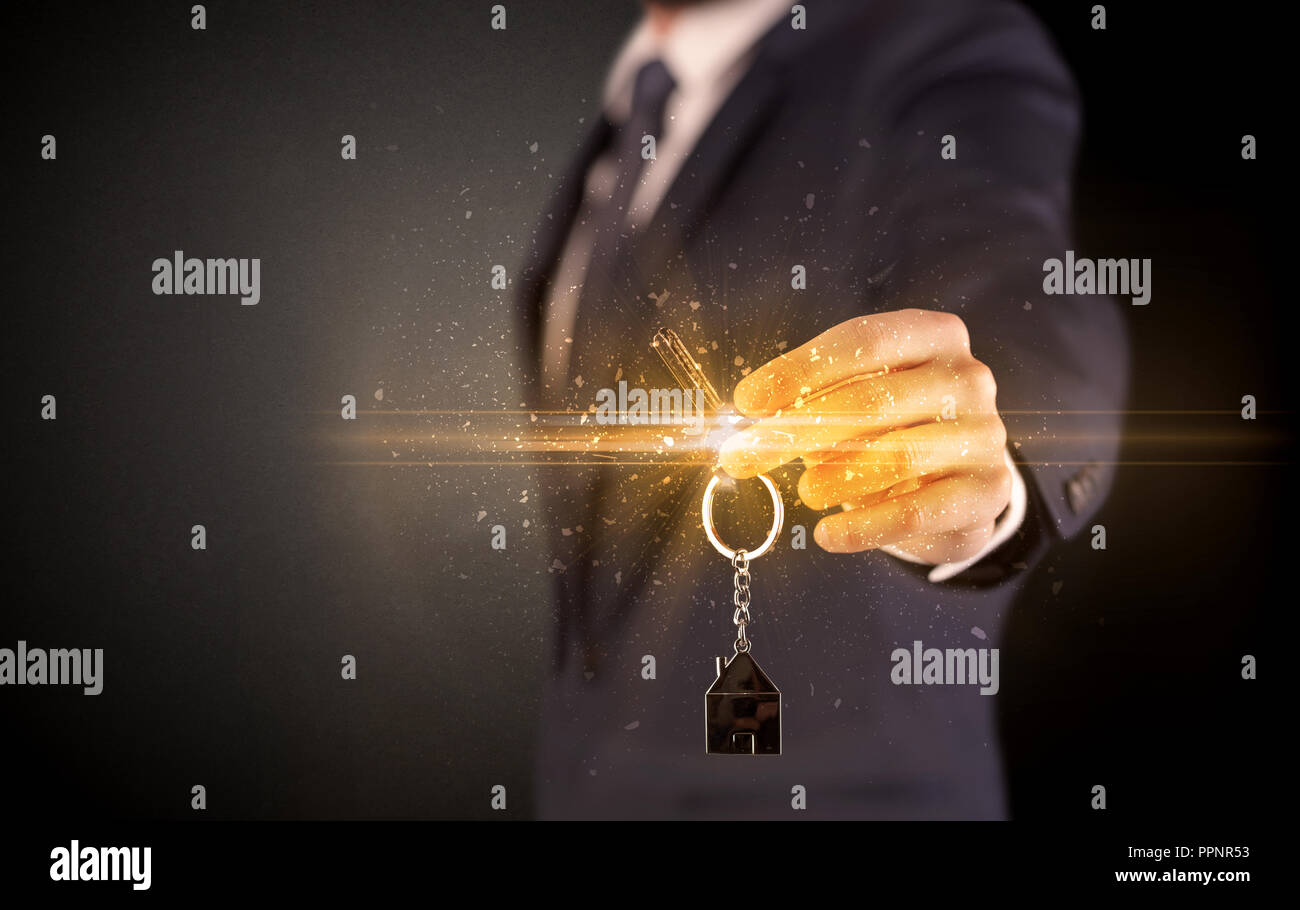 Businessman hand over shiny keys in dark suit with dark background ...