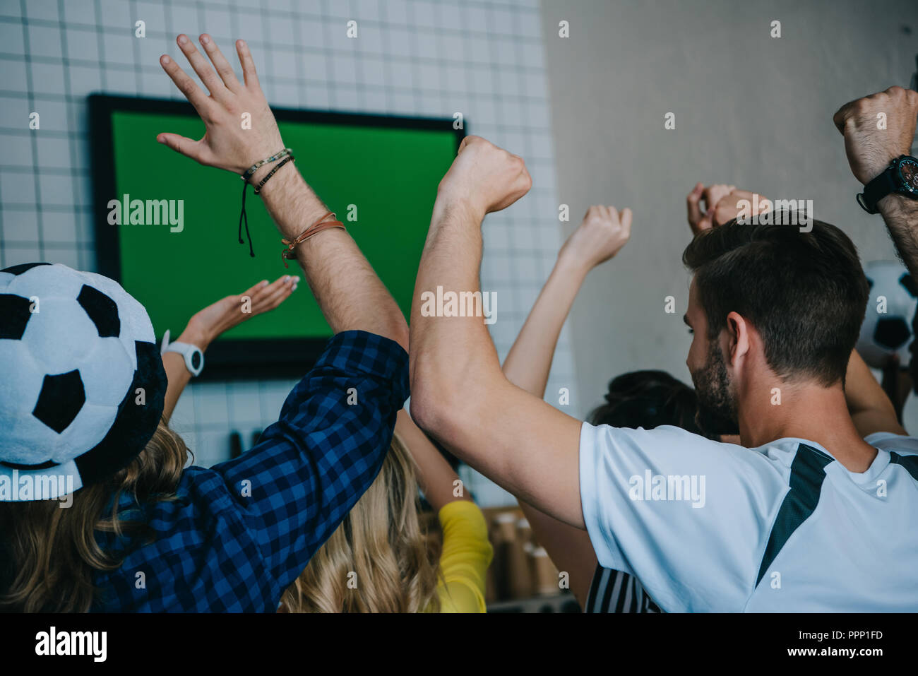 rear view of football fans celebrating and gesturing by hands during ...
