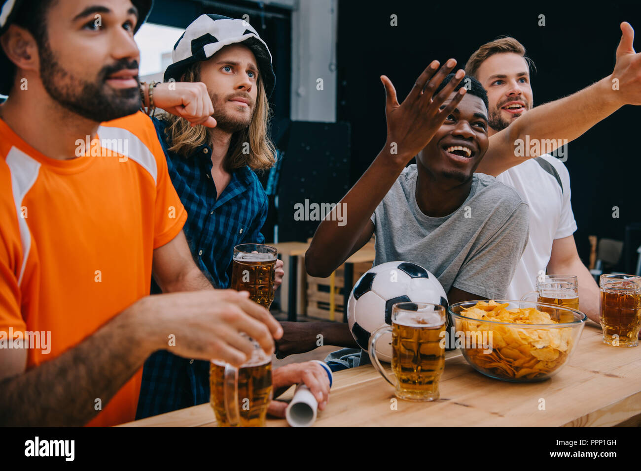 smiling multicultural group of male football fans gesturing by hands ...