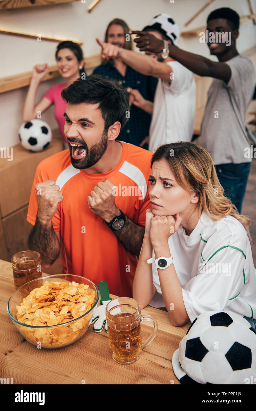 emotional multicultural football fans pointing by fingers and watching ...