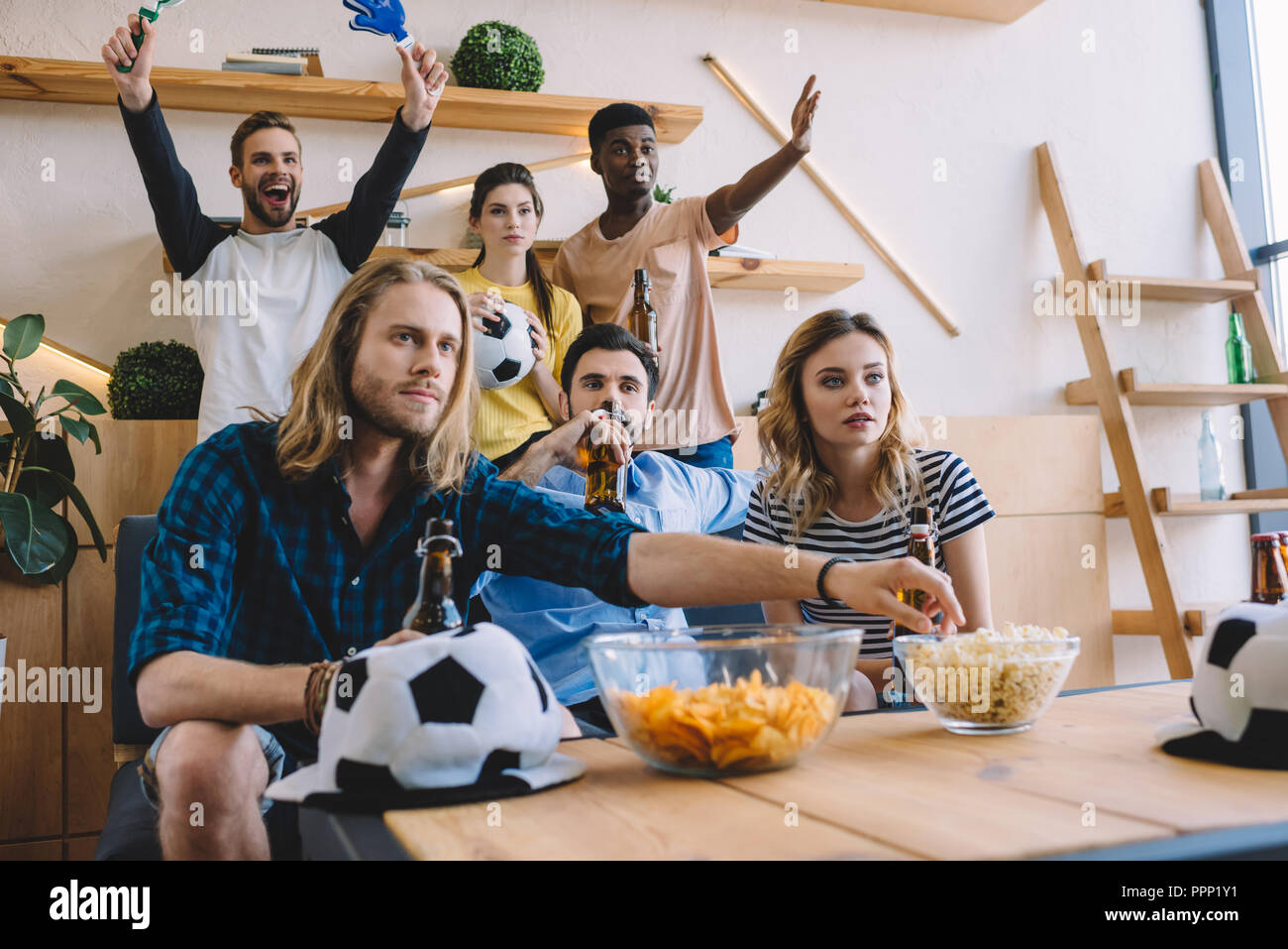 group of multicultural football fans watching soccer match at home ...