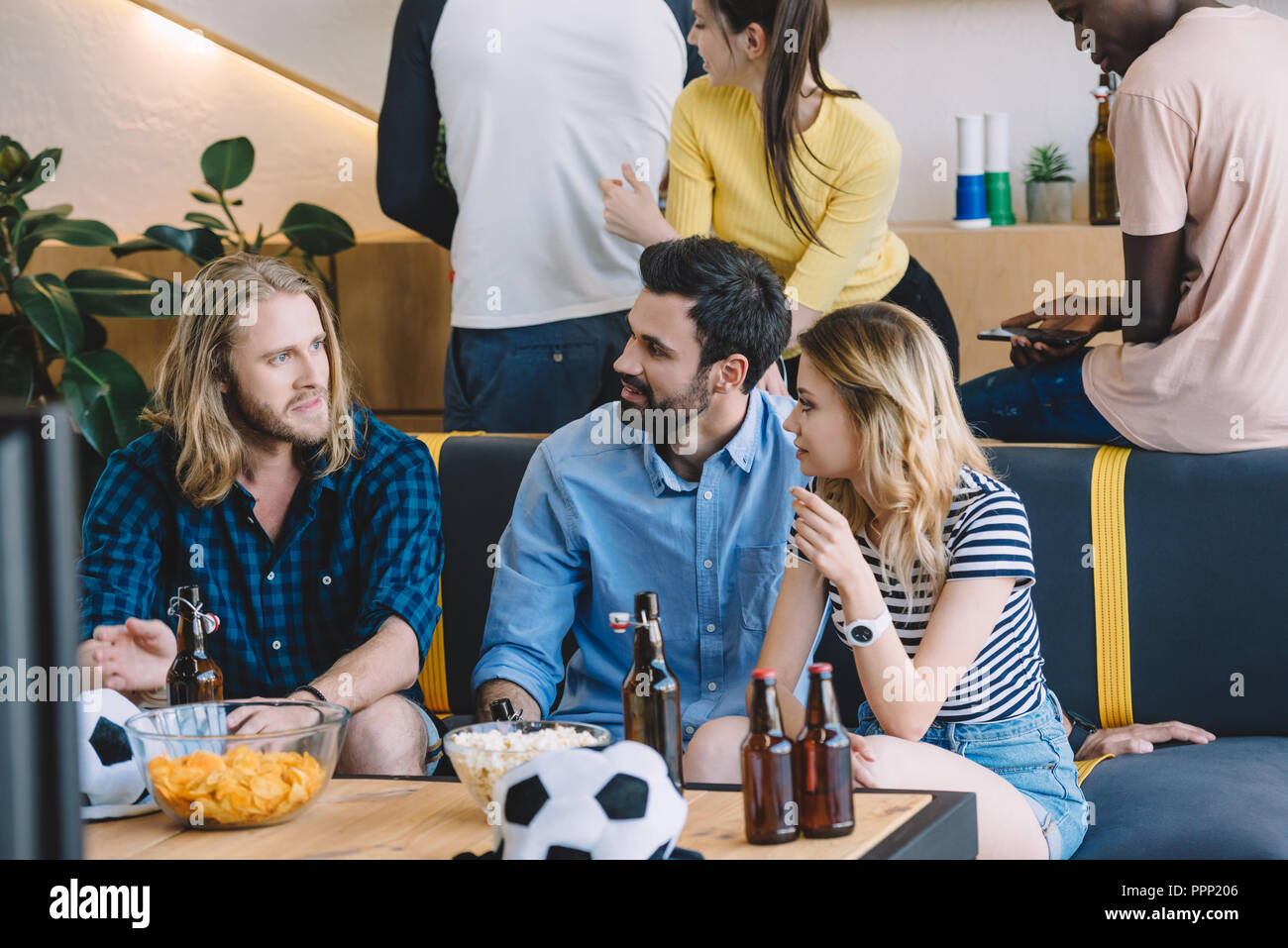 cropped image of group multicultural football fans sitting on sofa and ...