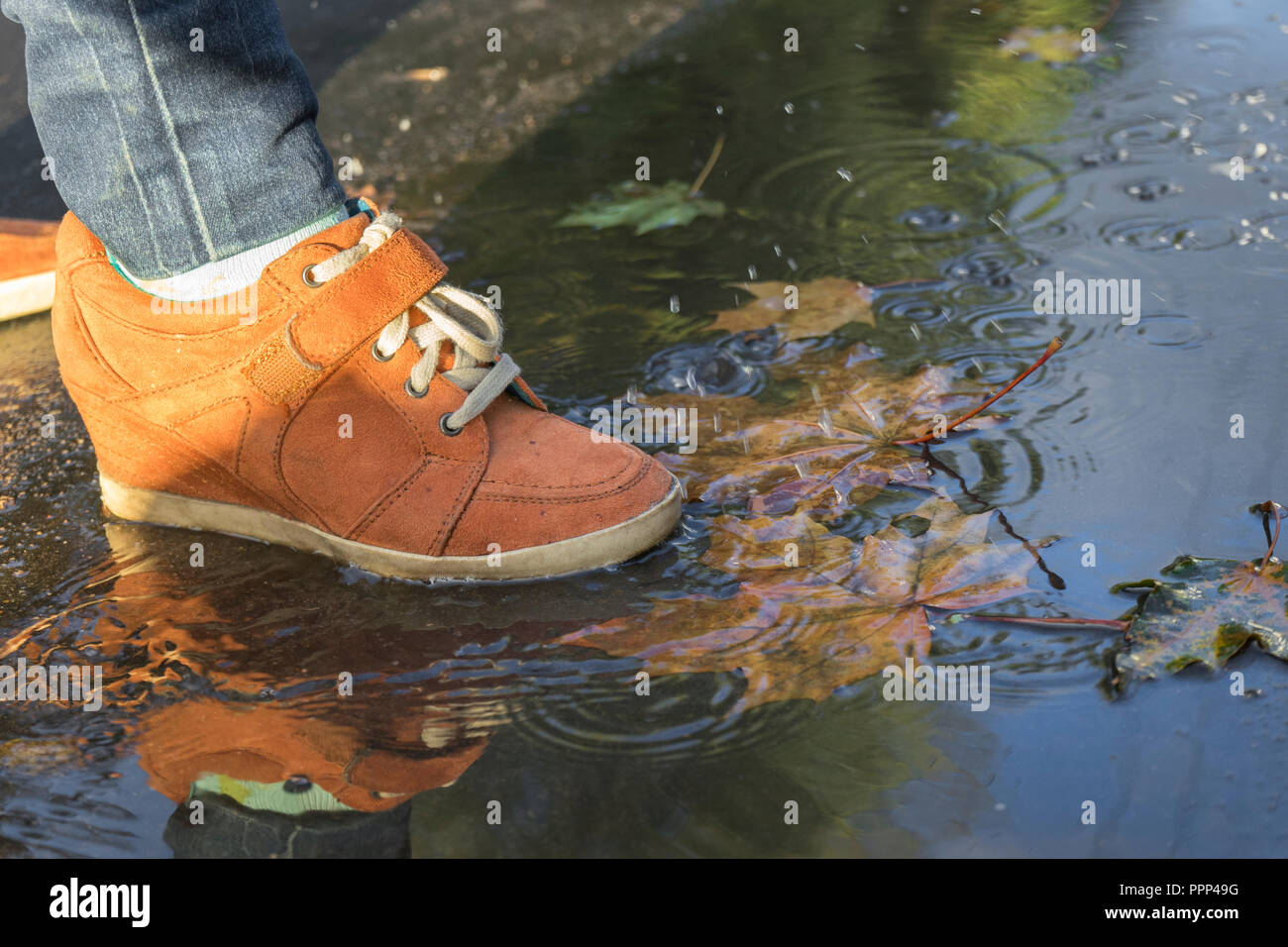 woman feet walking in a puddle in orange boots Stock Photo - Alamy