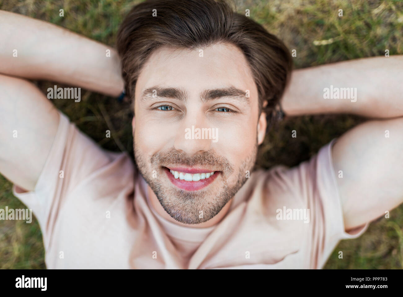 overhead view of smiling young man looking at camera while resting on ...