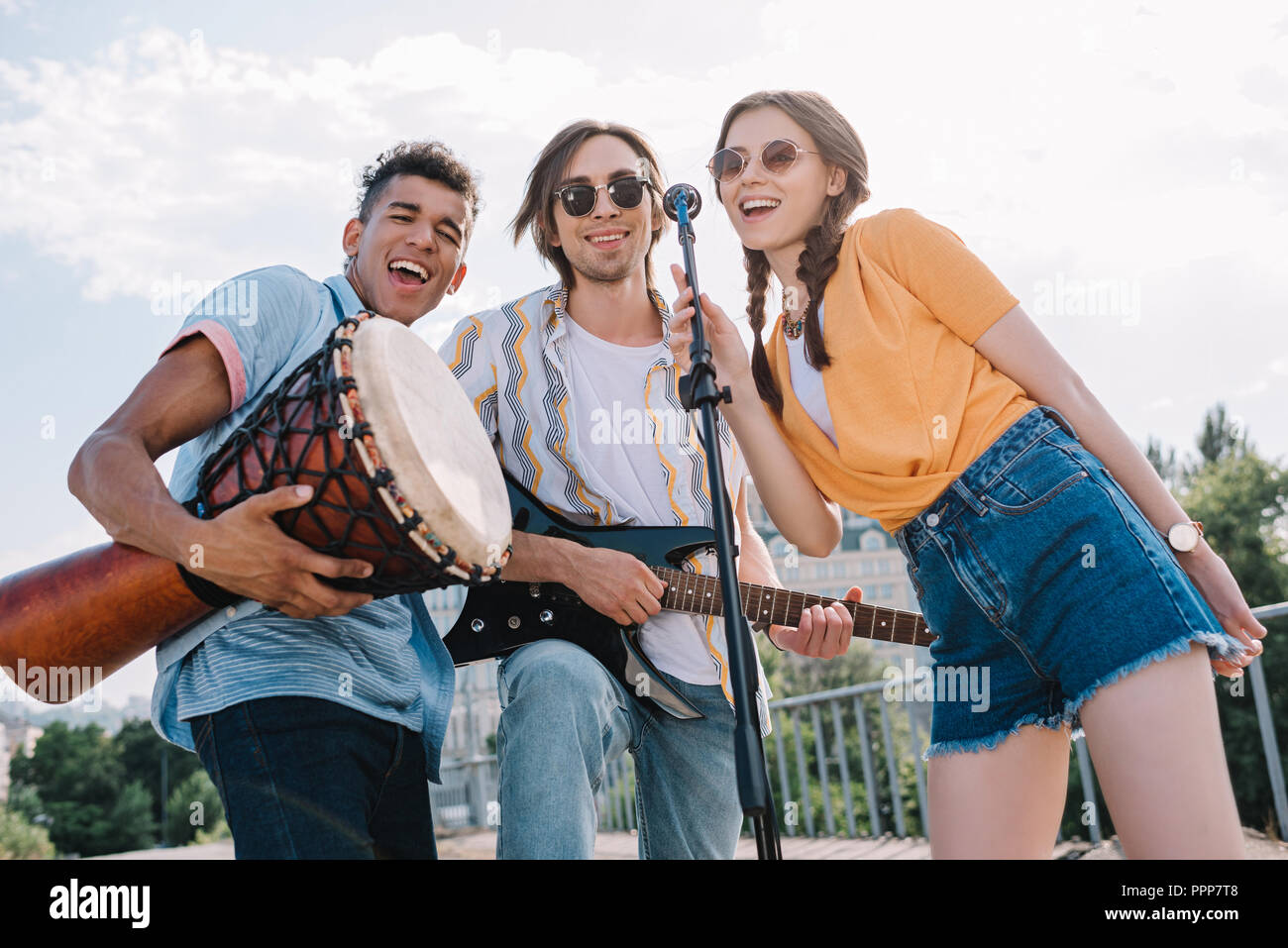 Young happy buskers singing by microphone at city street Stock Photo ...