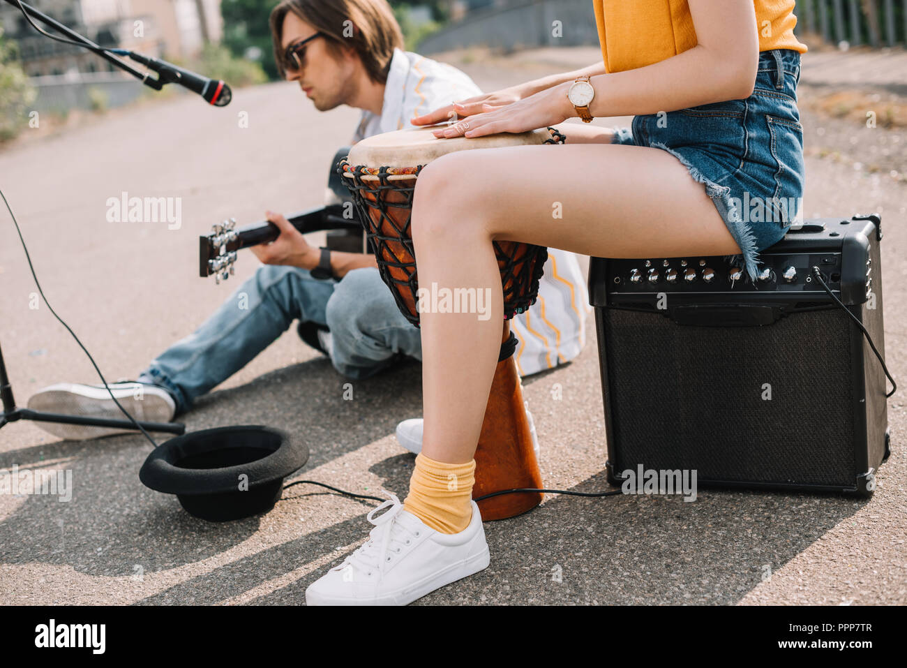 Woman with djembe and man with guitar performing on sunny city street ...
