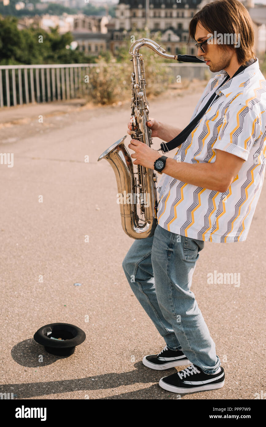 Young man with saxophone performing in urban environment Stock Photo ...