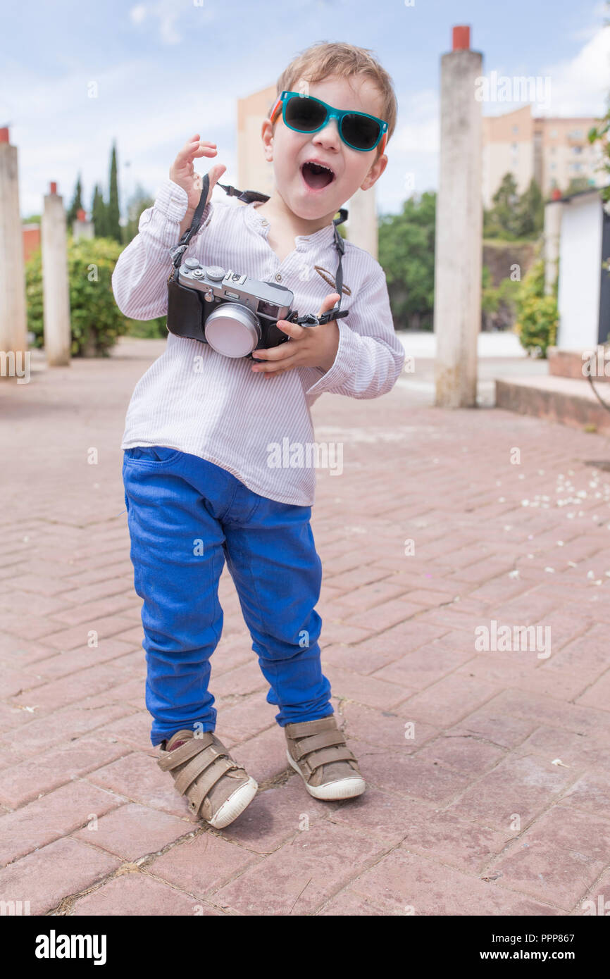 Cute happy boy with vintage photo camera as a little tourist at park ...