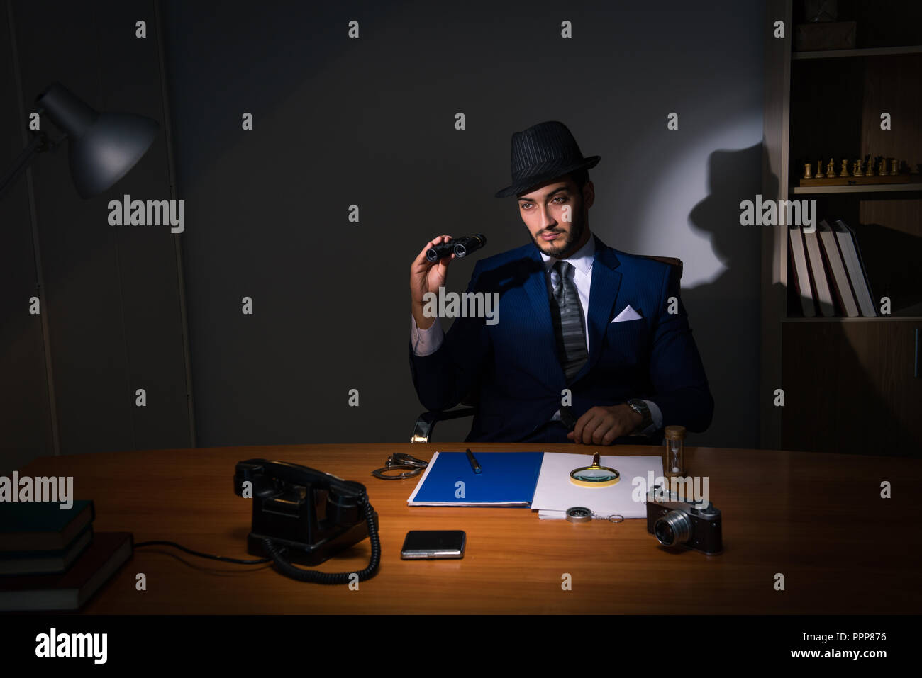 Detective sitting in dark room in vintage concept Stock Photo - Alamy
