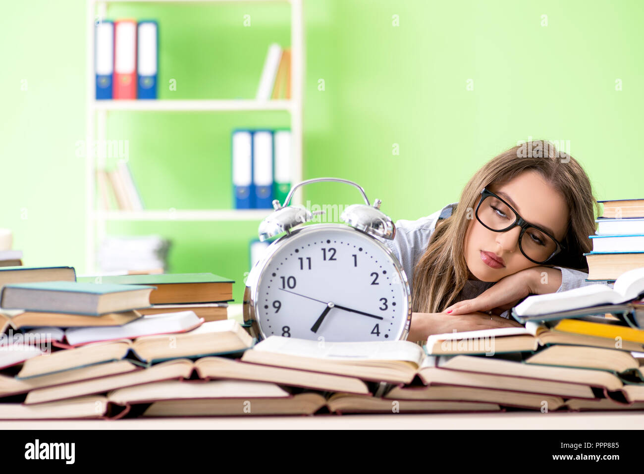 Young female student preparing for exams with many books in time ...