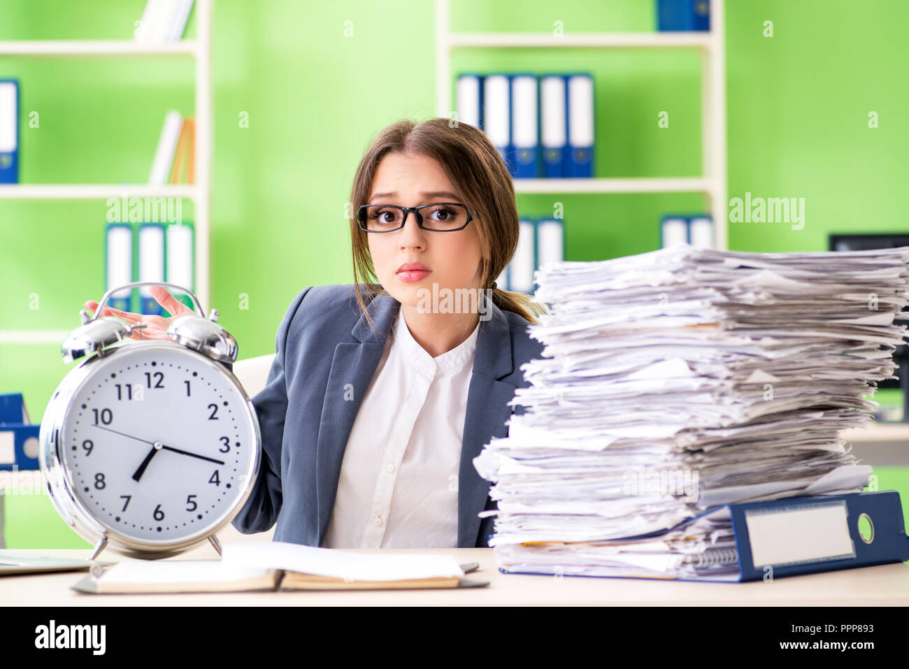 Young female employee very busy with ongoing paperwork in time ...
