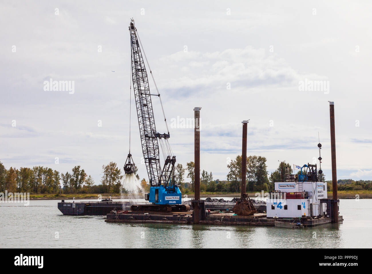 Floating crane and barge dredging the Steveston waterway near Vancouver ...
