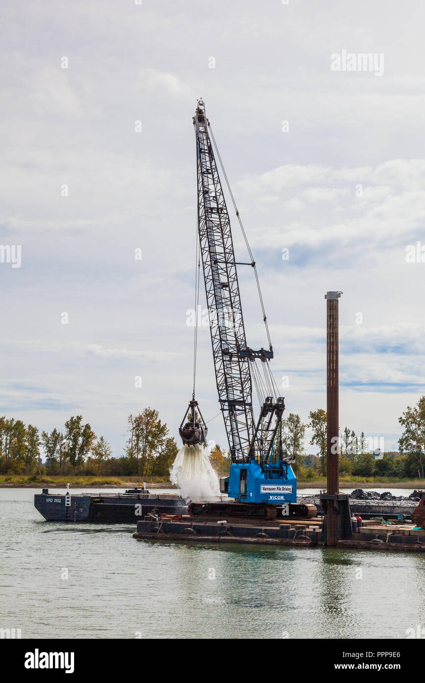 Floating crane and barge dredging the Steveston waterway near Vancouver ...