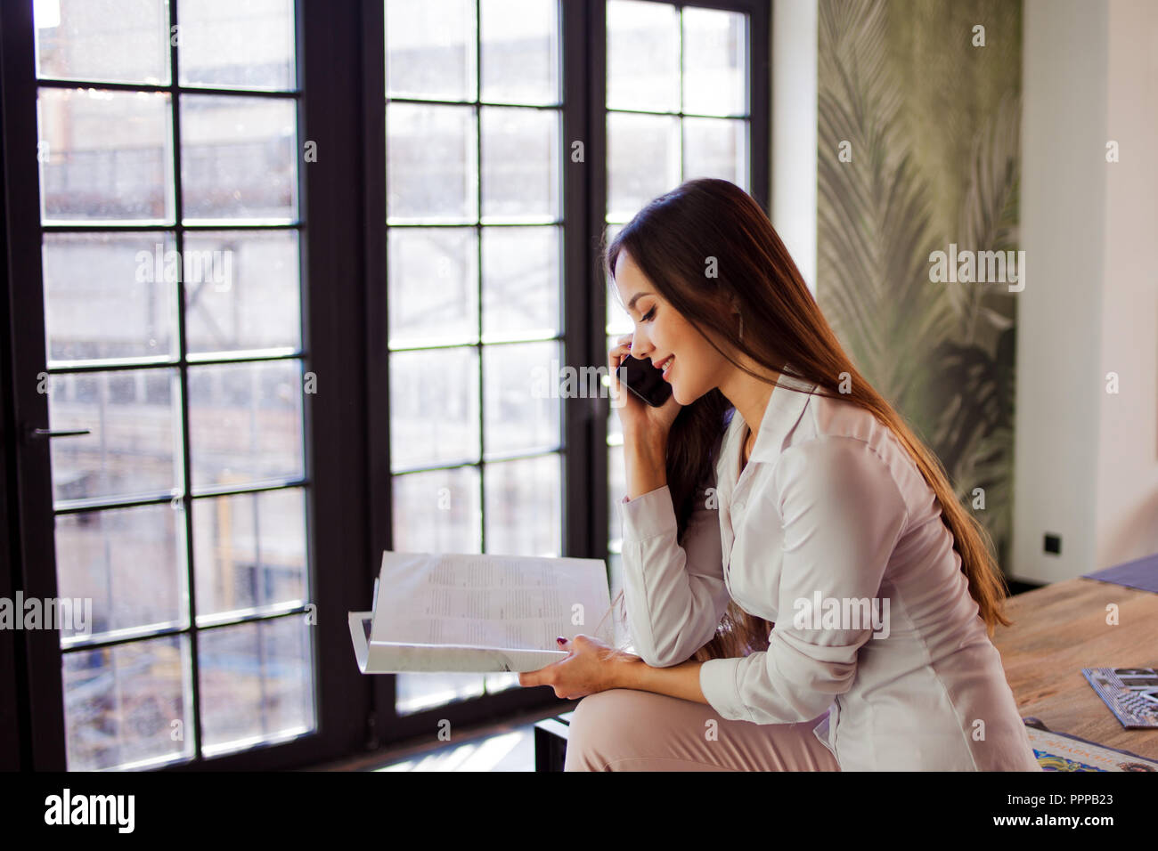 Happy young woman in comfortable loft style office. Business young brunette and talking on the ...