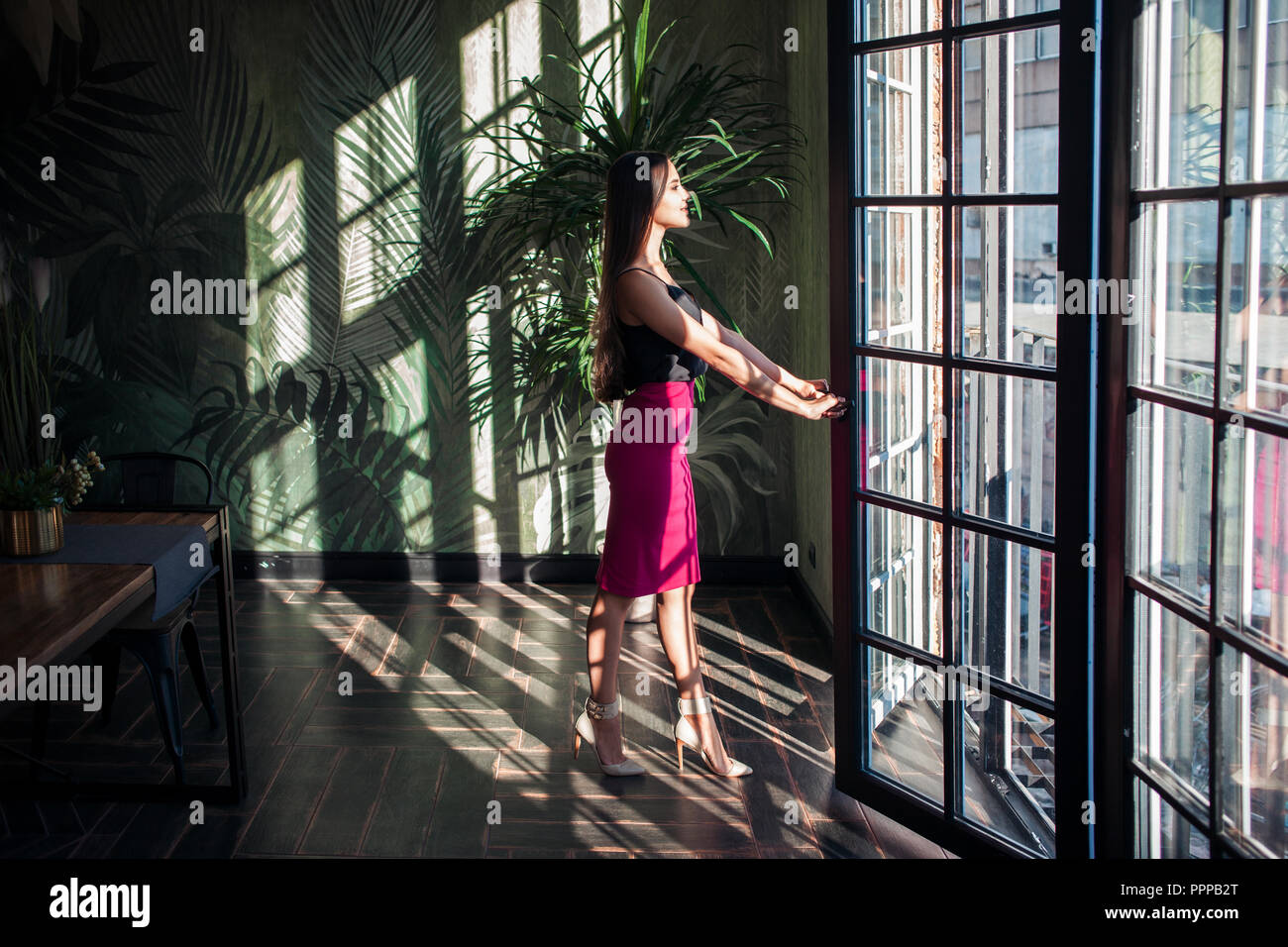 Beautiful young woman near a huge window. Attractive cute brunette in a ...