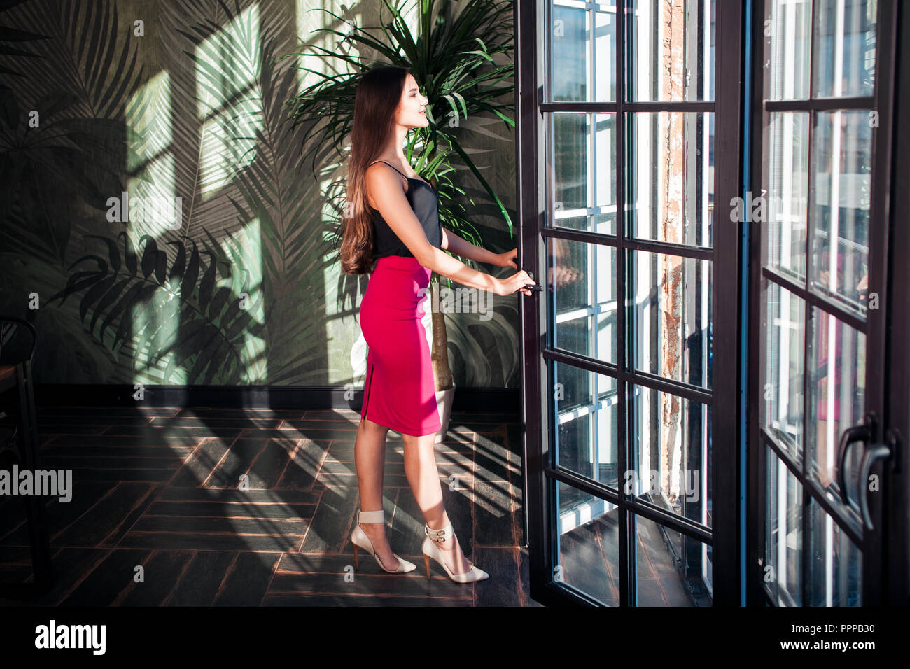 Beautiful young woman near a huge window. Attractive cute brunette in a ...