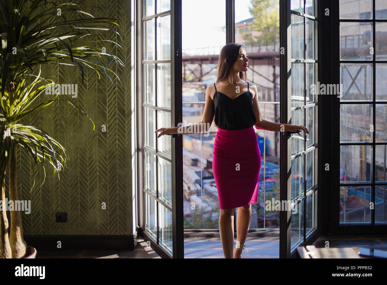 Beautiful young woman near a huge window. Attractive cute brunette in a ...