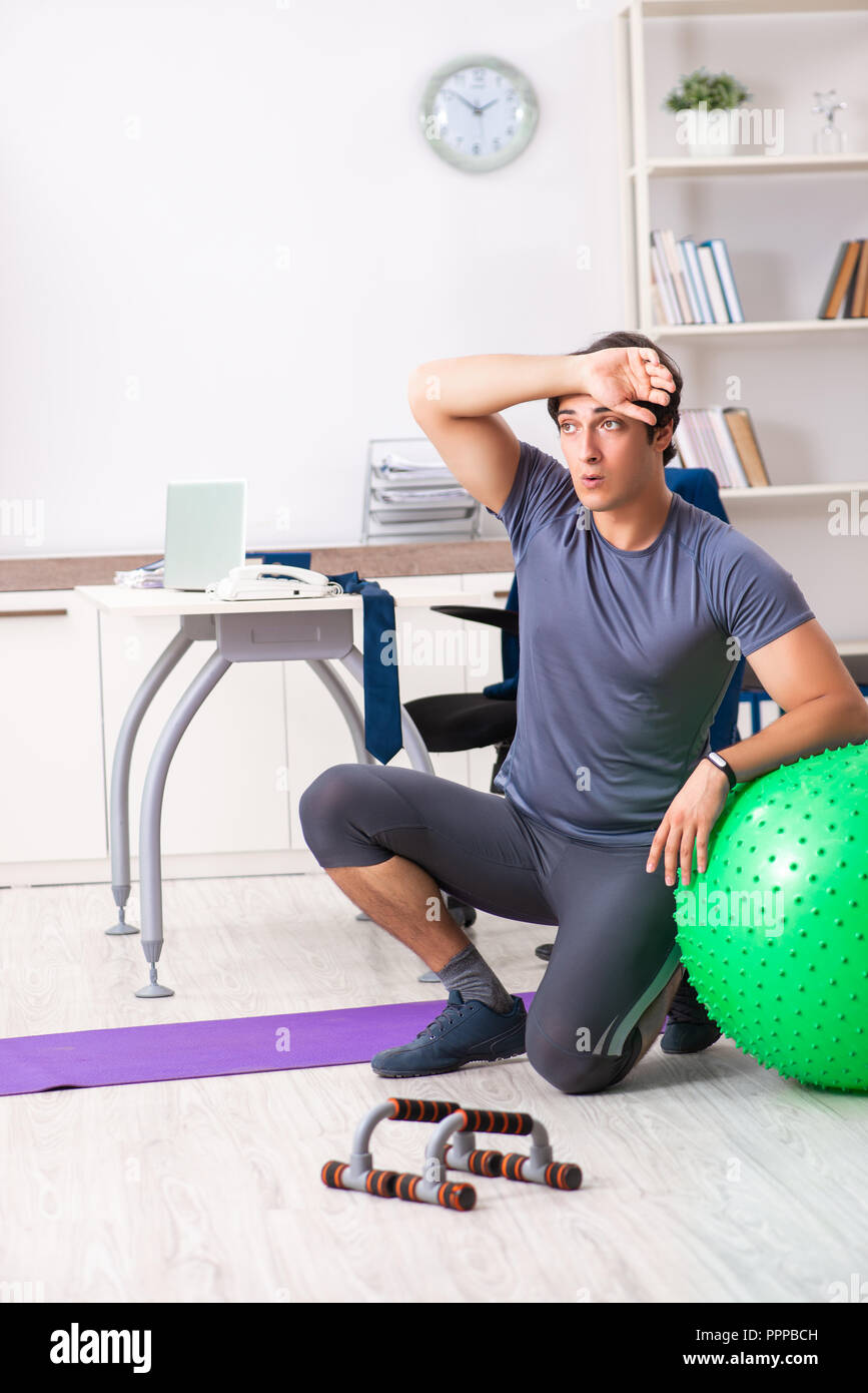 Young male employee exercising in the office Stock Photo - Alamy