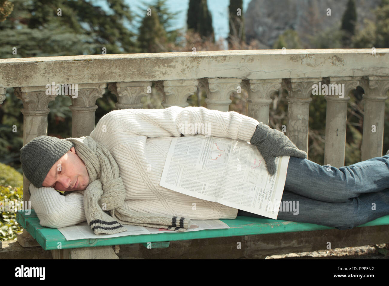 Man sleeping on a bench under newspaper Stock Photo - Alamy