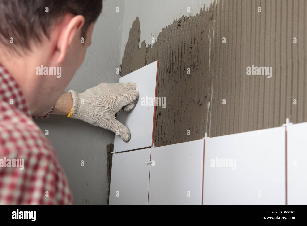 Contractor installing tiles on a wall Stock Photo - Alamy
