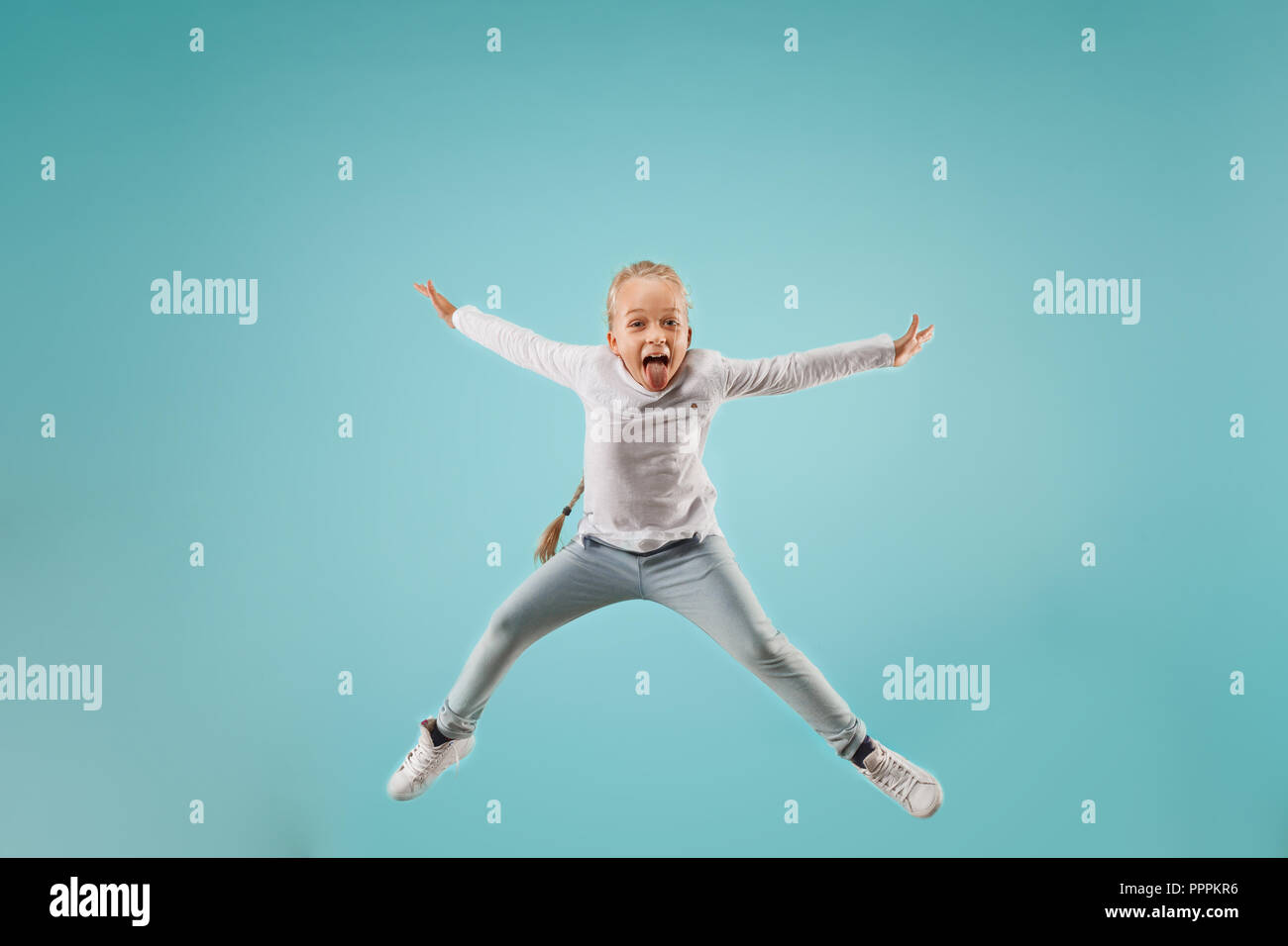 Adorable small child at blue studio. The girl is jumping and smiling ...