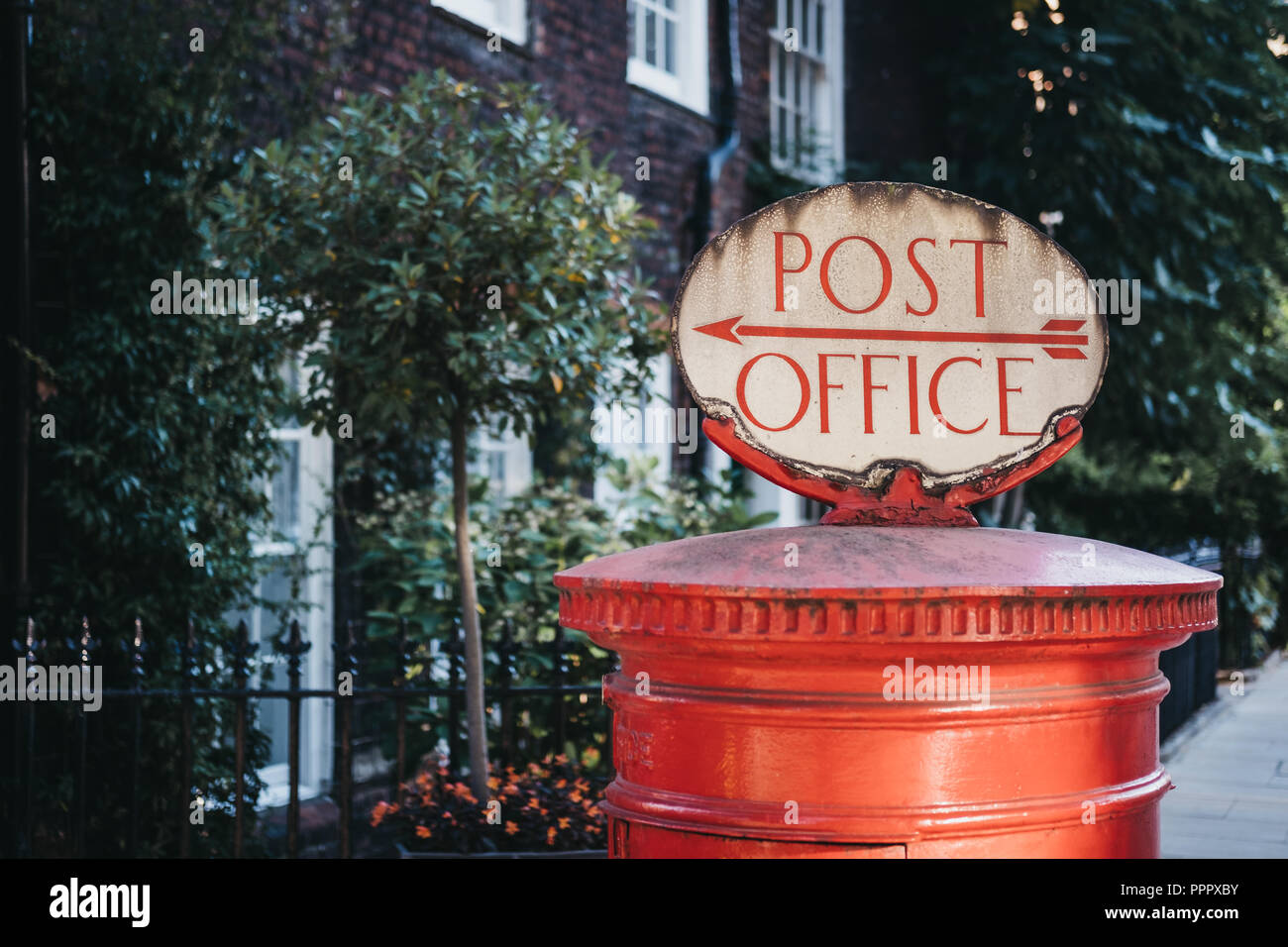 Red post box with a retro Post Office directional sign on top in London ...