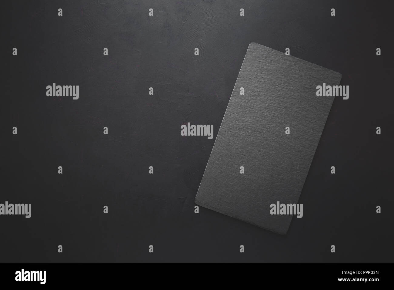 Top view on rectangle black slate plate on rustic dark background. Copy ...