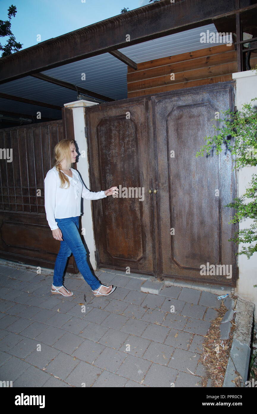 blonde woman open gate, enter to home Stock Photo - Alamy