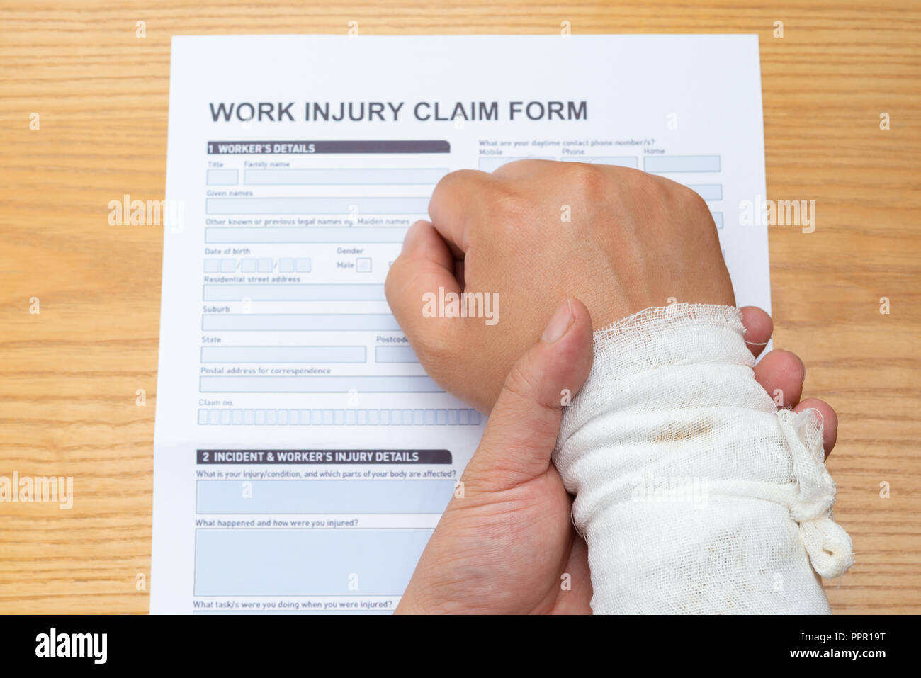 man with wrapped hand on top of a work injury claim form Stock Photo ...