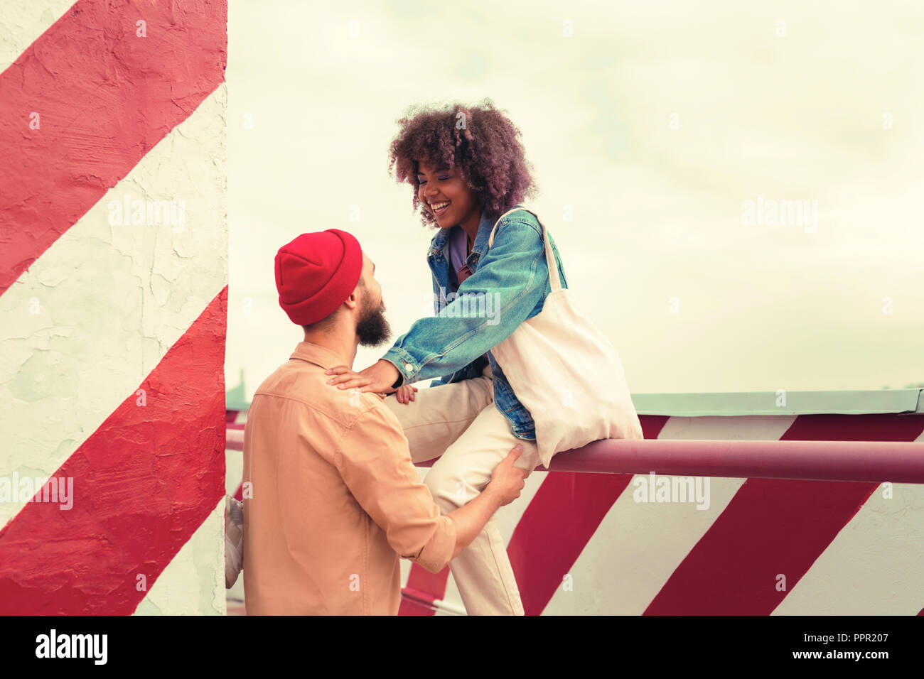 Young woman sitting on hand rail and smiling to her beloved man Stock ...