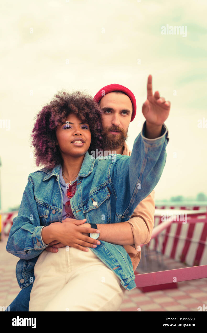 Handsome man looking at the sky while his smiling girlfriend pointing ...