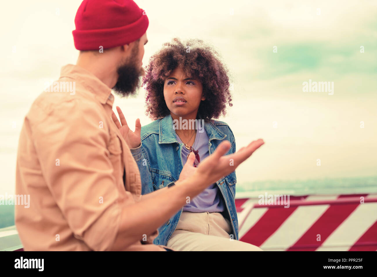 Young couple using gestures while having serious talk Stock Photo - Alamy
