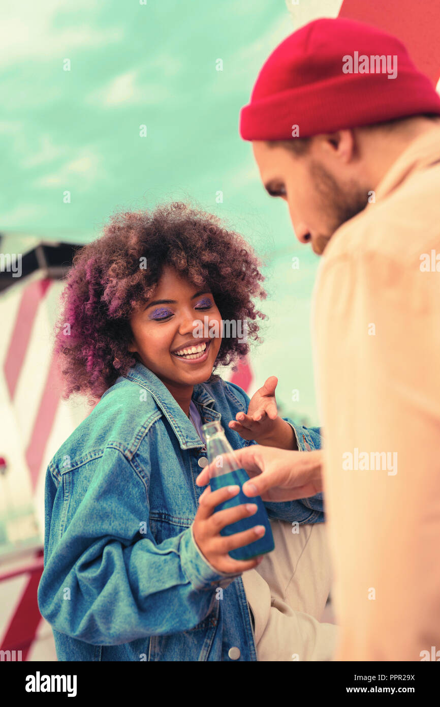 Young couple sitting together and sharing the bottle of blue drink ...