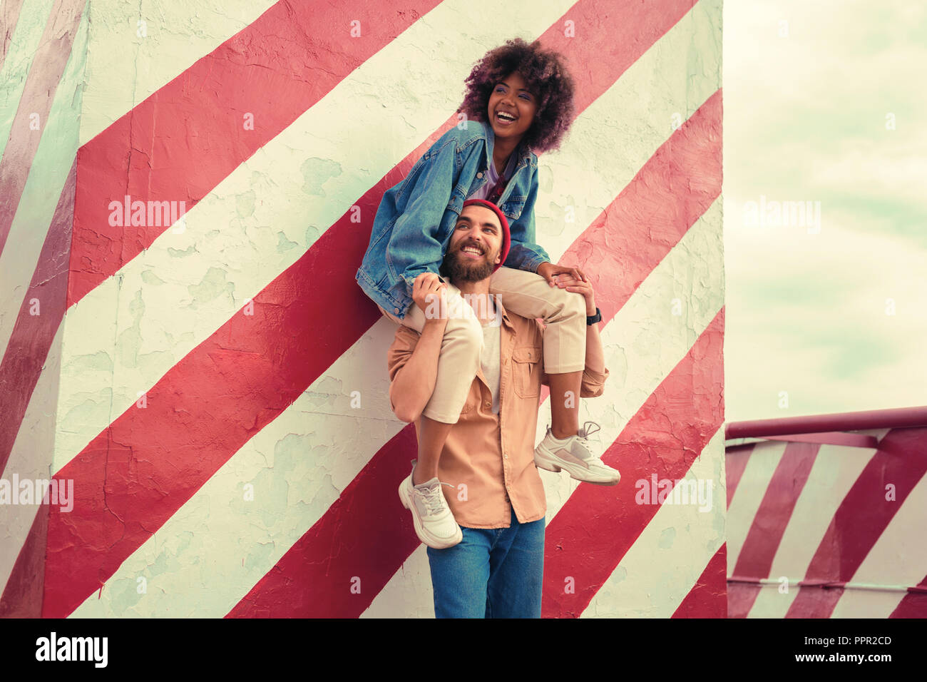 Young man feeling his strength while carrying pretty girlfriend on his ...