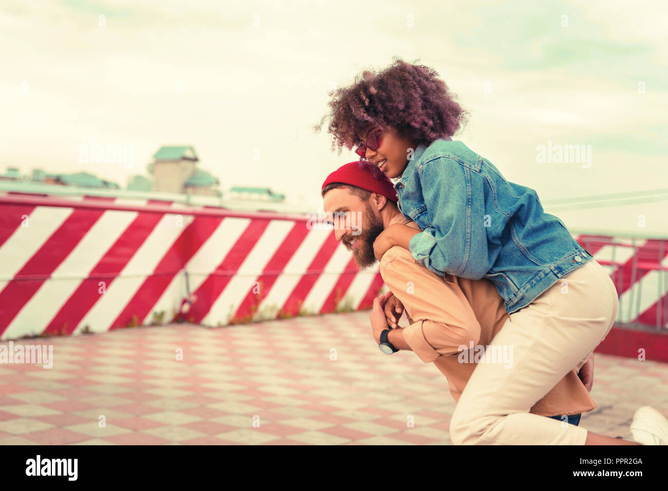 Positive girl smiling while jumping on the back of her boyfriend Stock ...