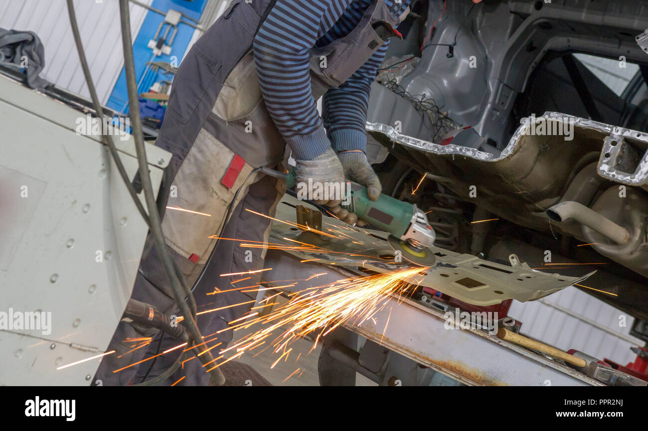 The mechanic works the car part with a grinder. Many sparks Stock Photo ...
