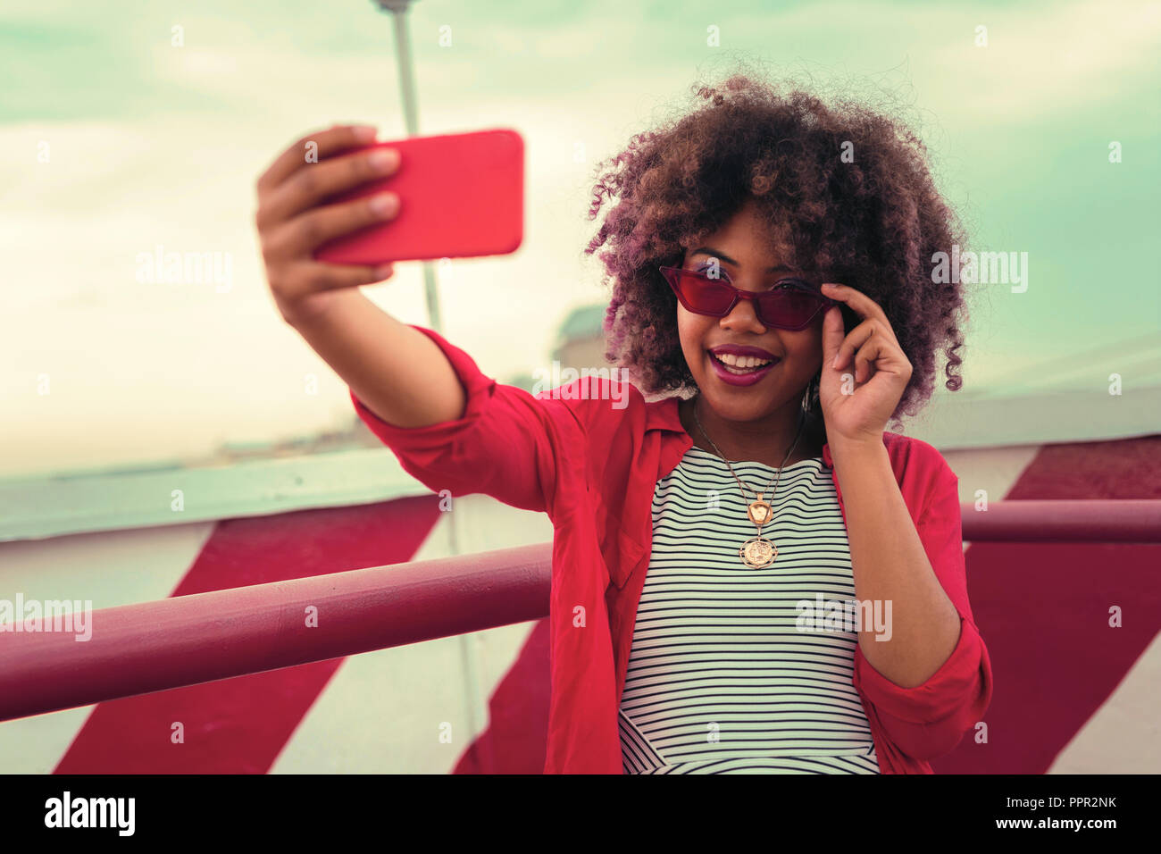 Attractive young woman wearing red glasses and taking wonderful selfies ...