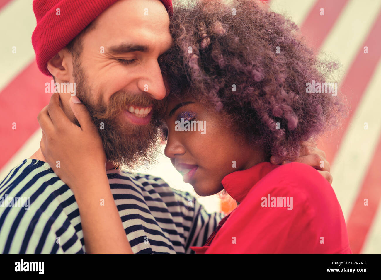 Beautiful young couple standing with their eyes closed and hugging ...
