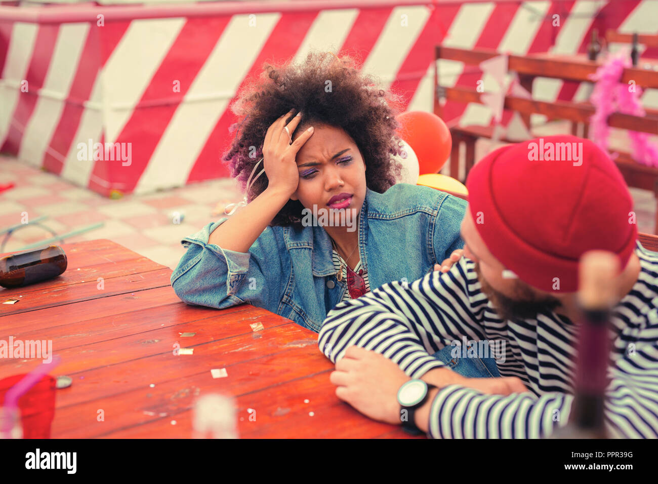 Young woman looking at her boyfriend and having headache after party ...