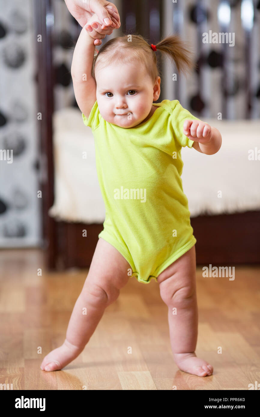 Baby girl taking first steps with mother's help at home Stock Photo - Alamy
