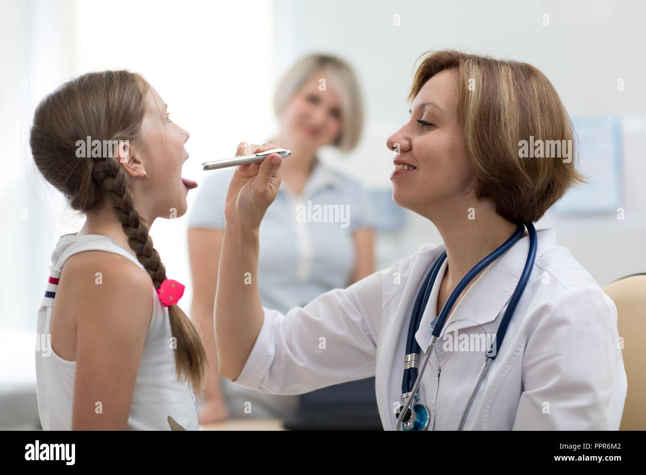 Woman doctor examining little girl mouth at office. Doctor at hospital ...