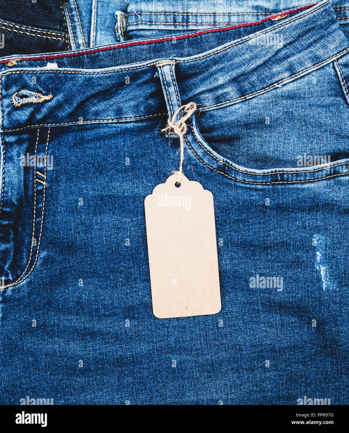 blue jeans with a brown paper empty tag on a rope, full frame, close up ...