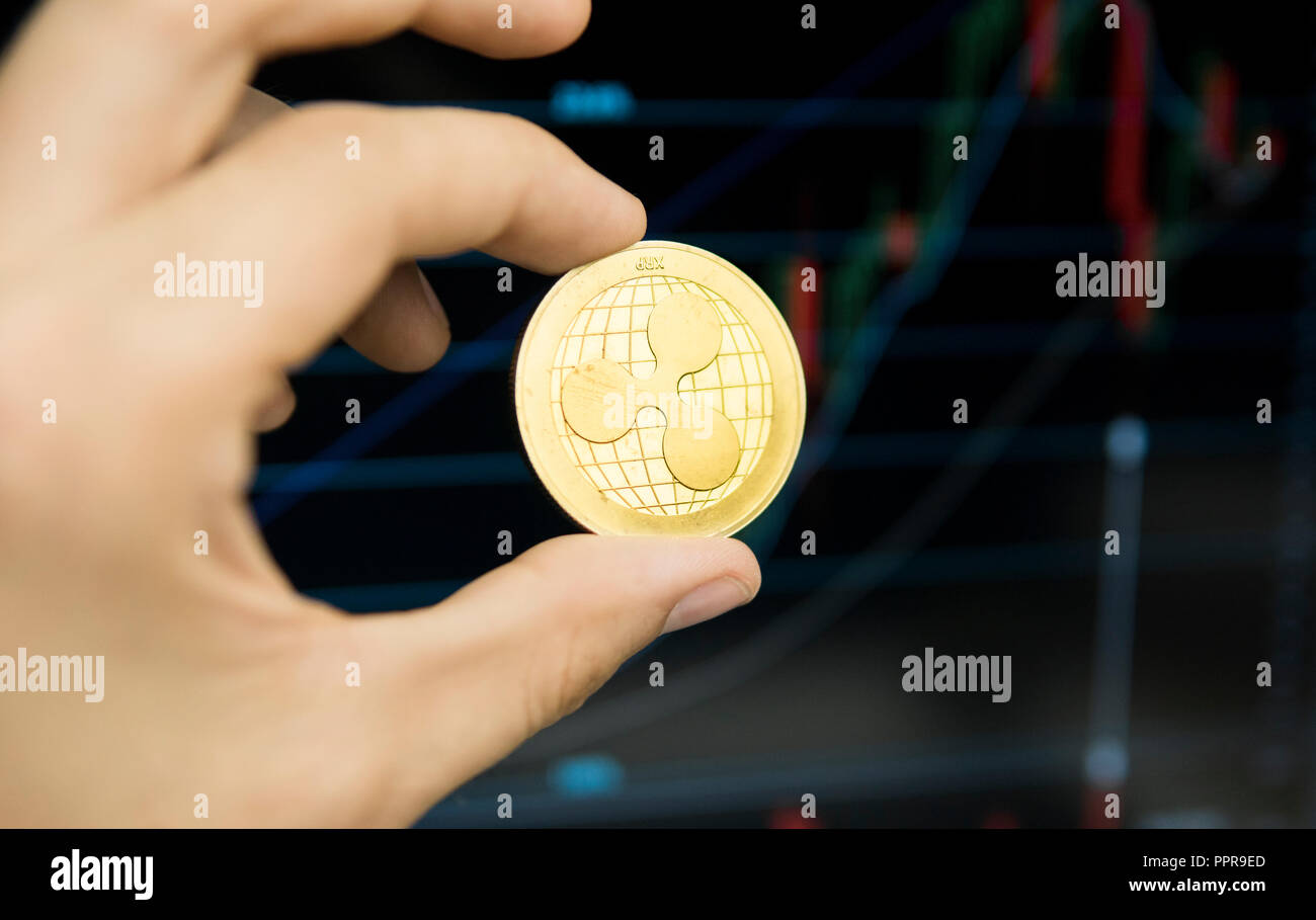 Male businessman hand holding Ripple coin on a background of growth ...