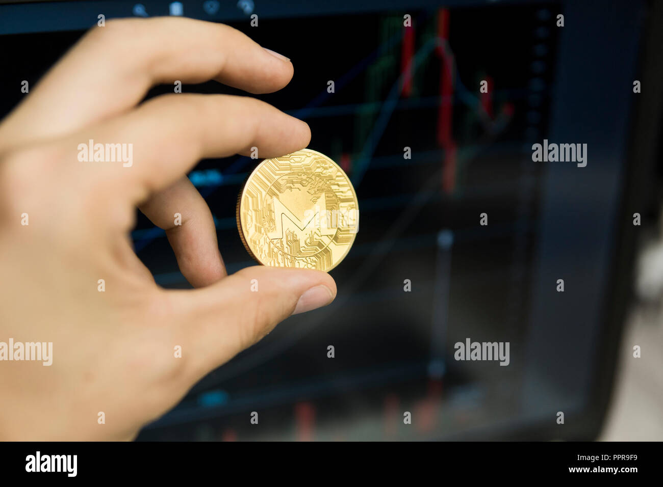 Male businessman hand holding Monero coin on a background of growth ...
