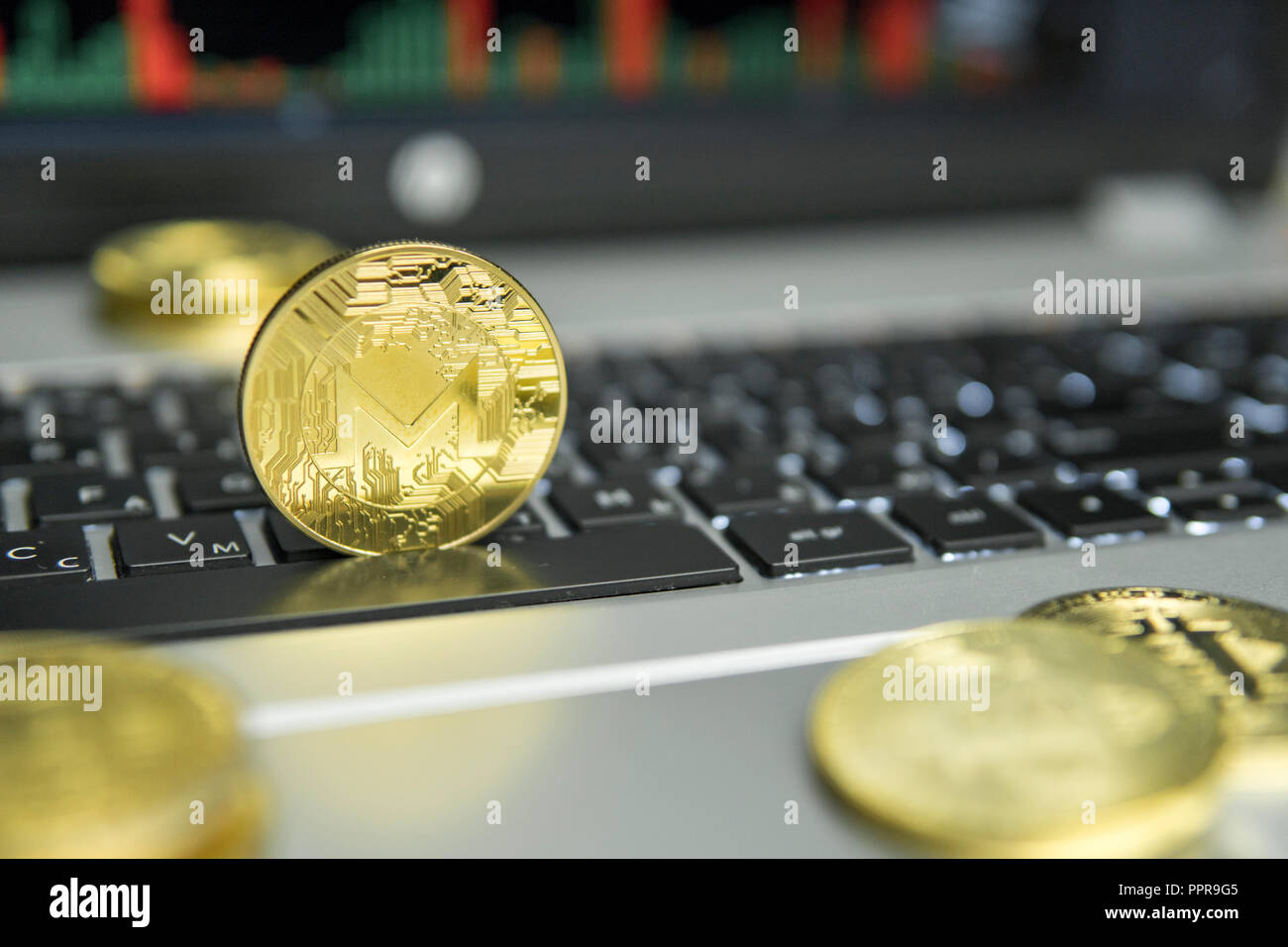 Golden Monero coin with gold coins lying around on a black keyboard of ...