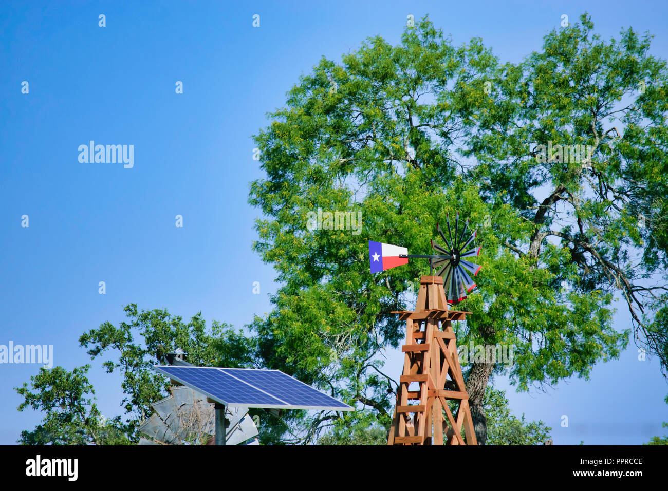 Solar Water well with Texas Windmill in front of summer green trees ...