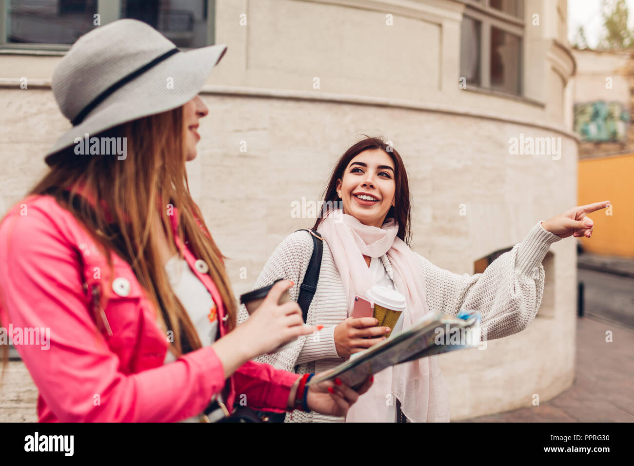 Two women tourists searching for right way using map on city street ...