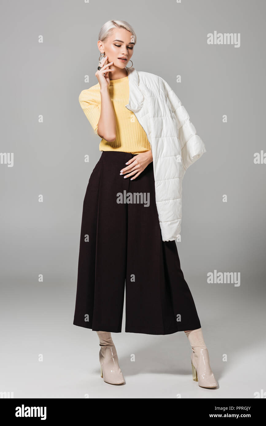 stylish female model posing with jacket over shoulder isolated on grey ...