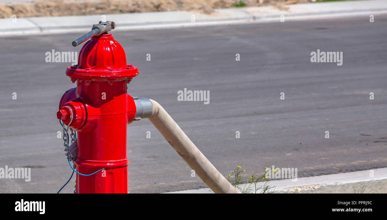 Hose and wrench secured to a red fire hydrant Stock Photo - Alamy